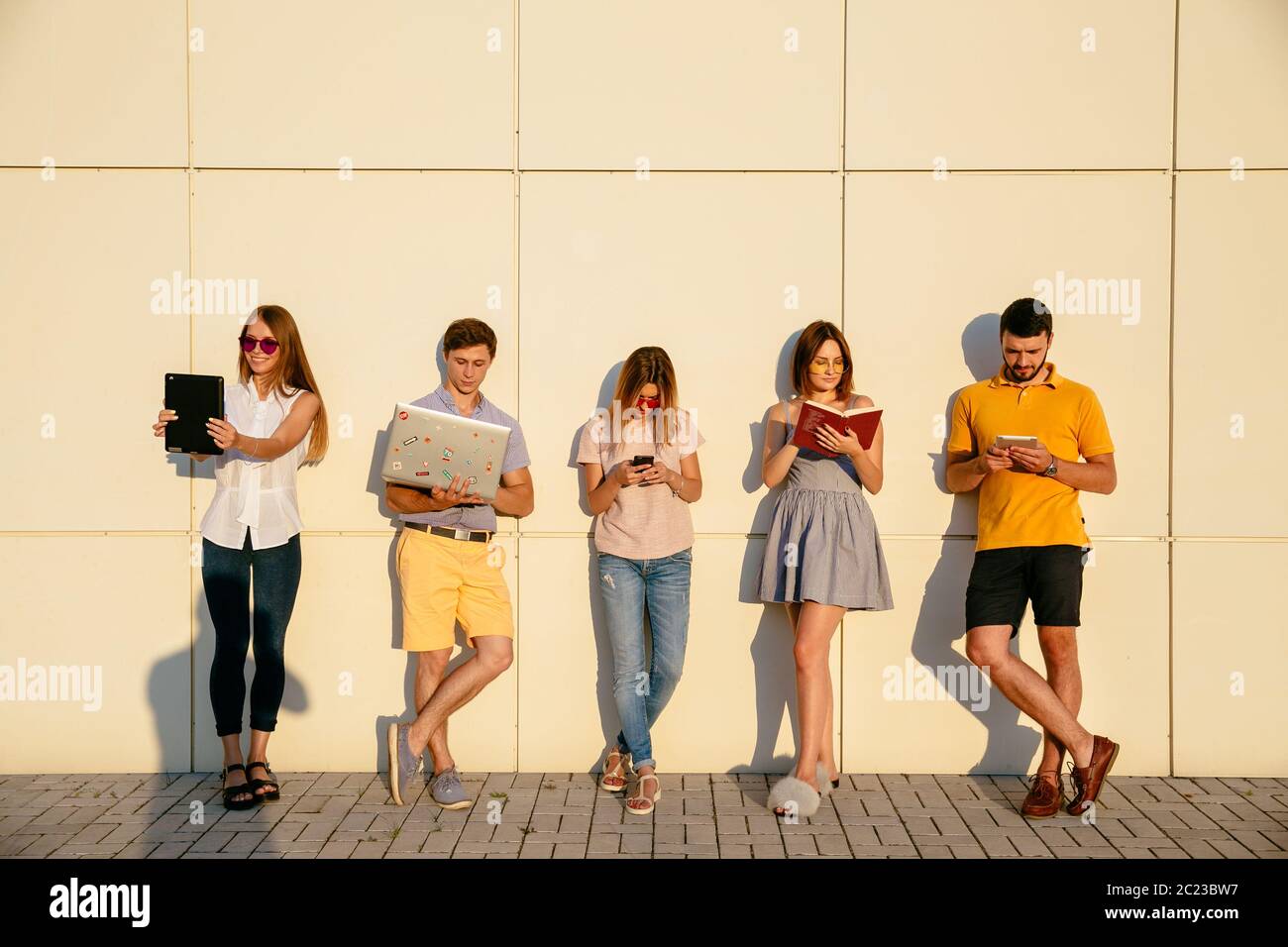 Beautiful young students are using gadgets, reading book and smiling ...