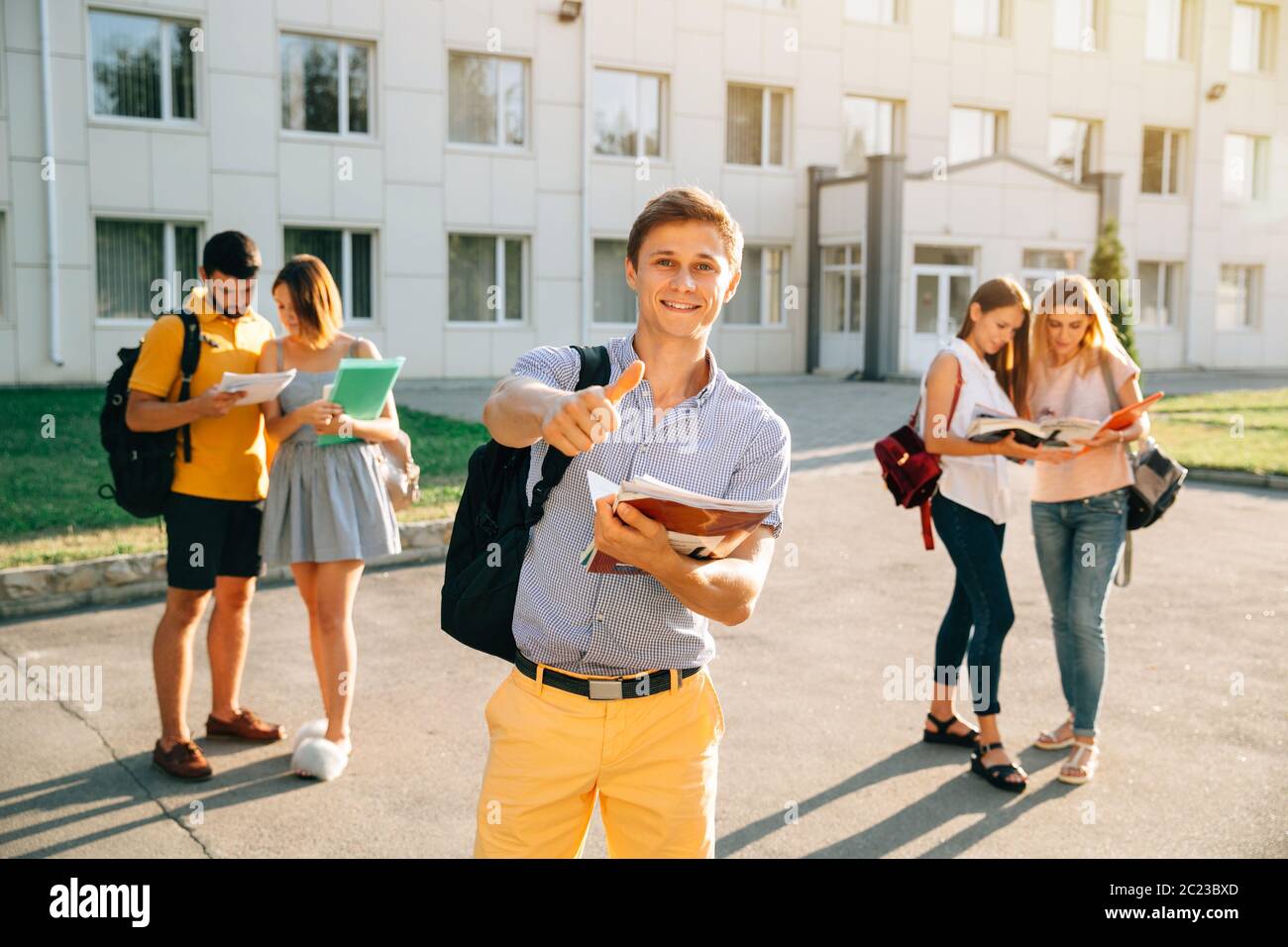 Happy student with note-books and backpack smiling and showing thumb up ...