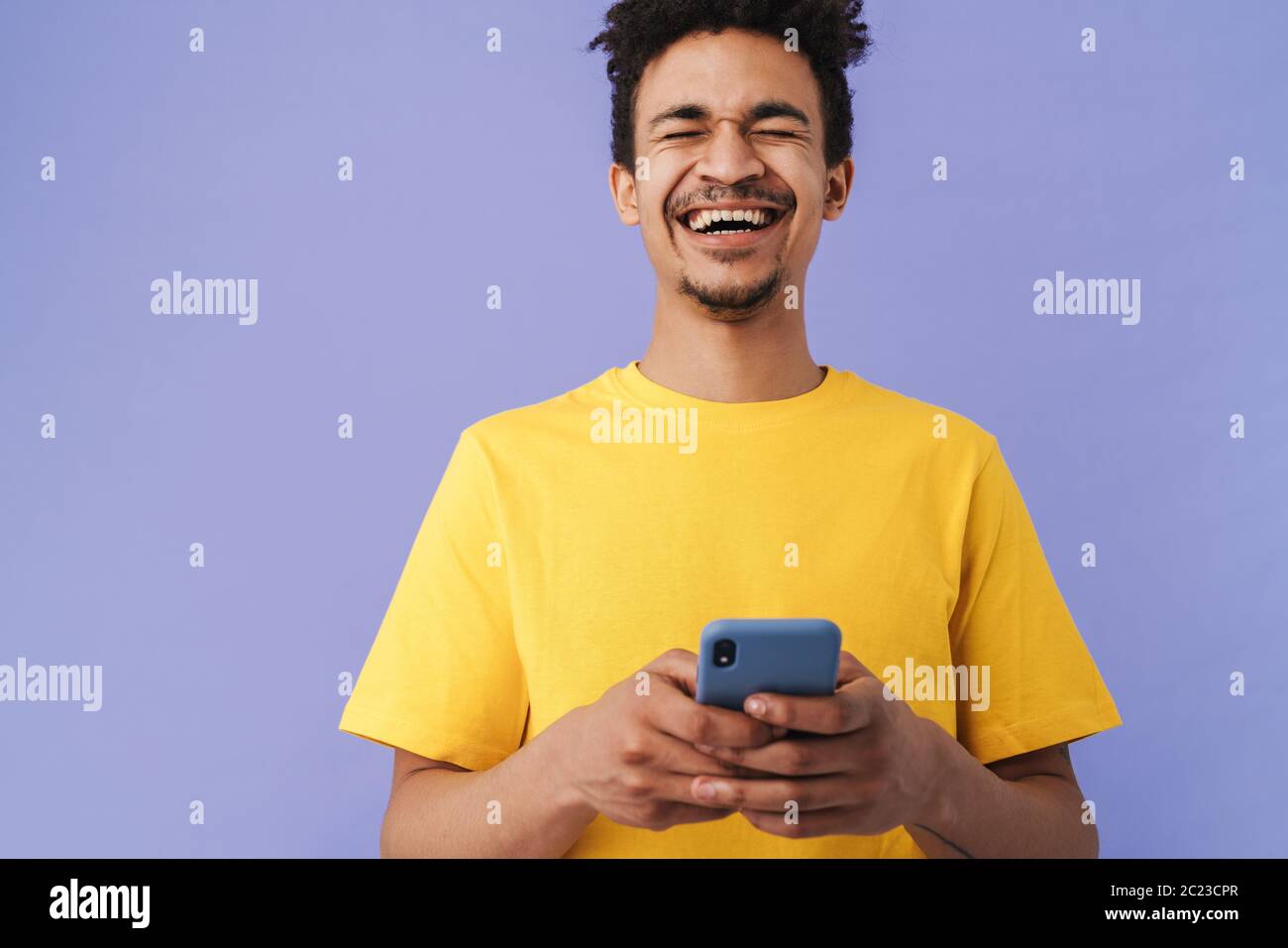 Photo of funny african american man laughing and using smartphone ...