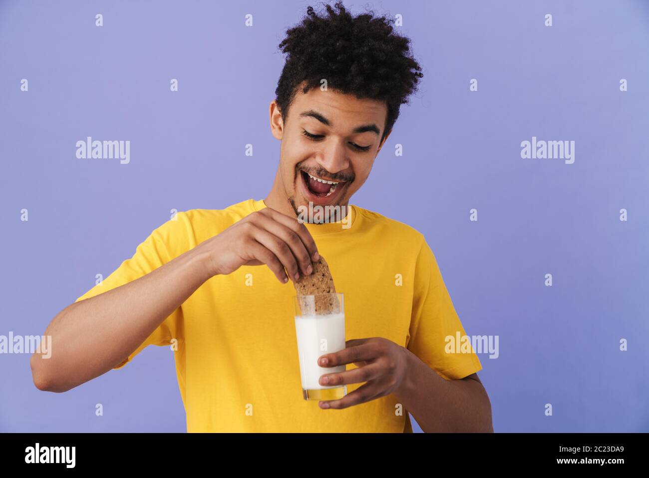 Photo of pleased african american man smiling while eating cookie with ...