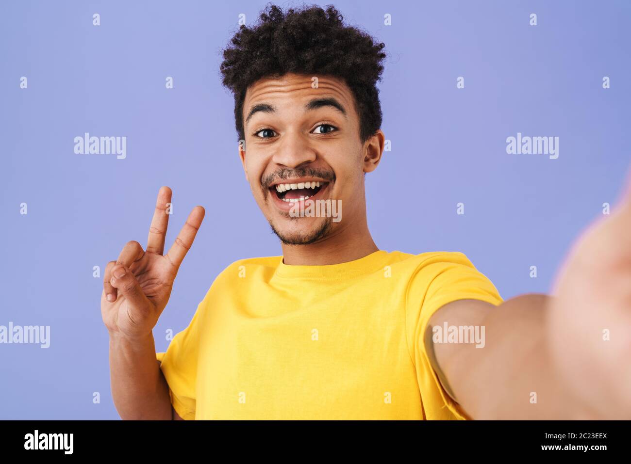 Photo of cheerful african american man taking selfie photo and gesturing peace sign isolated ...