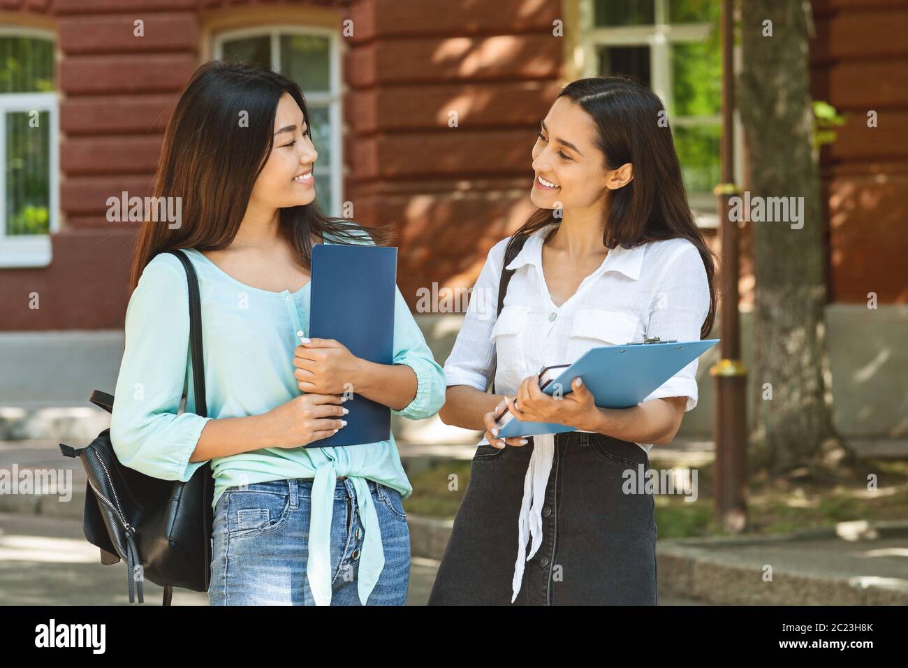 College Friendship. Two female students chatting outdoors after classes ...