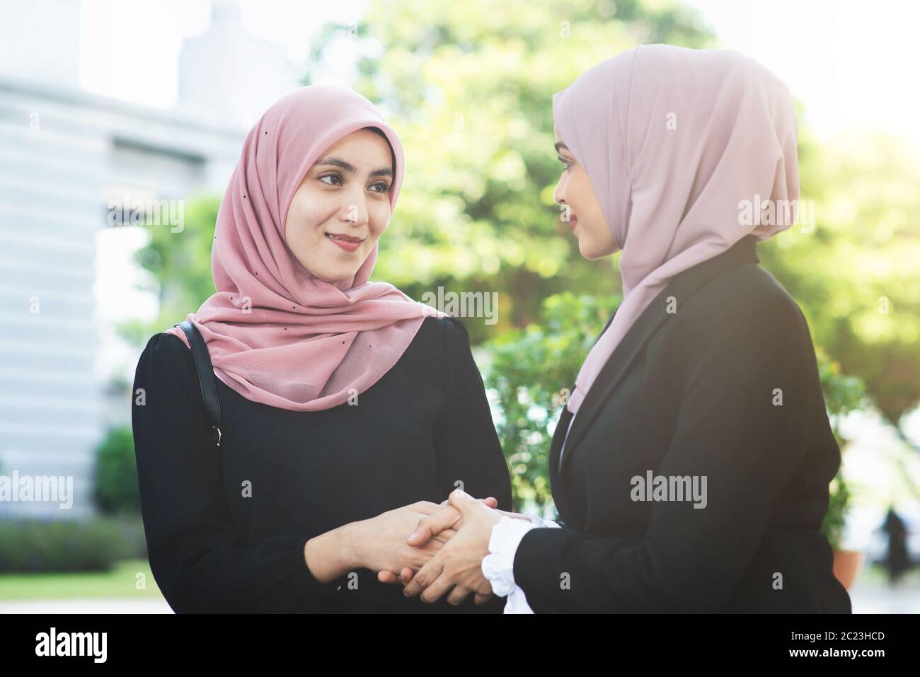Muslim business women greeting, handshake and smiling Stock Photo - Alamy