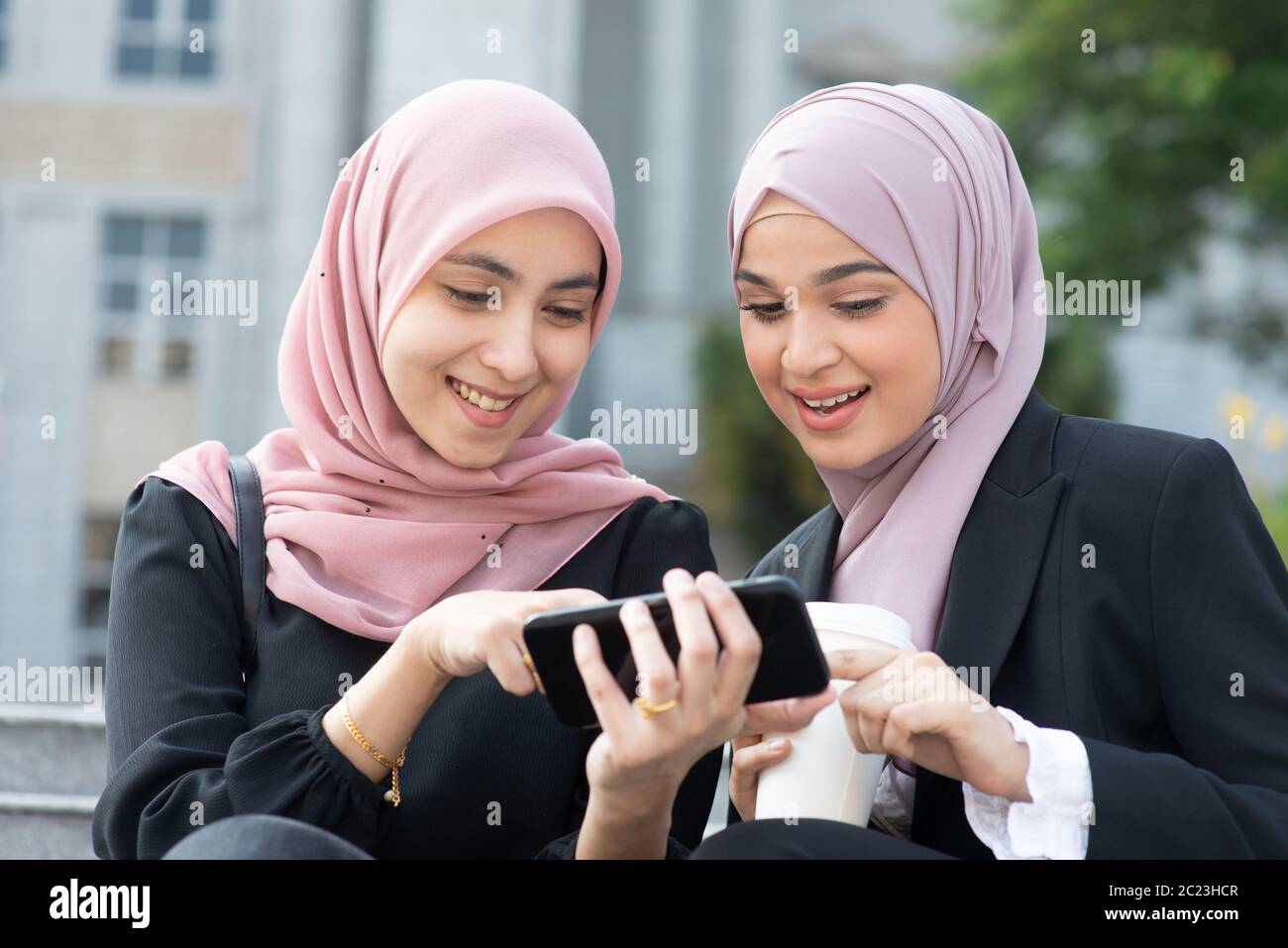 Muslim women using smart phone, sharing and laughing Stock Photo - Alamy