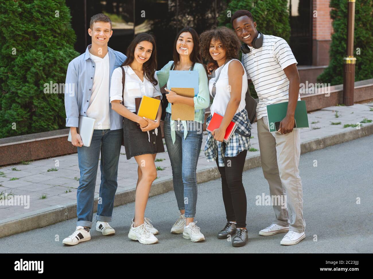 Multiethnic group of students standing outdoors in school campus with ...