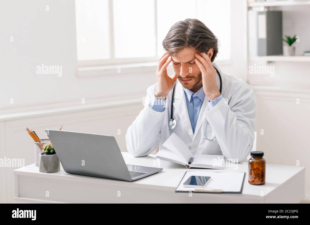 Stressed doctor suffering from headache at workplace Stock Photo - Alamy