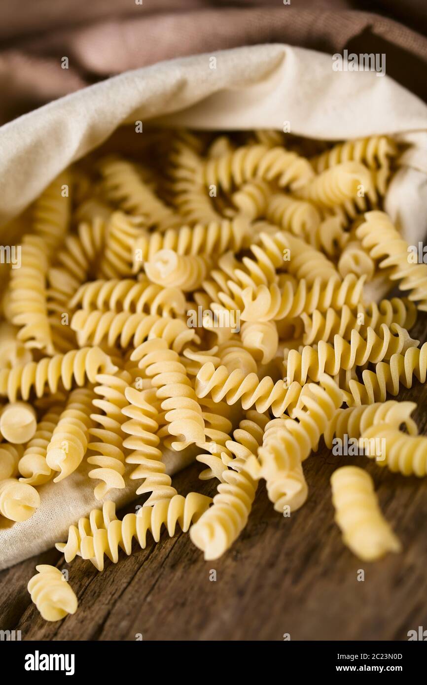Raw rotini or fusilli pasta in bag, photographed on rustic wood ...