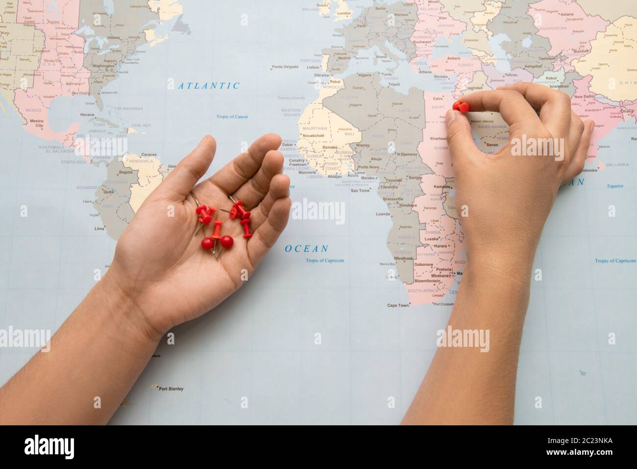 Close-up of unrecognizable tourist putting red pins on paper map while ...