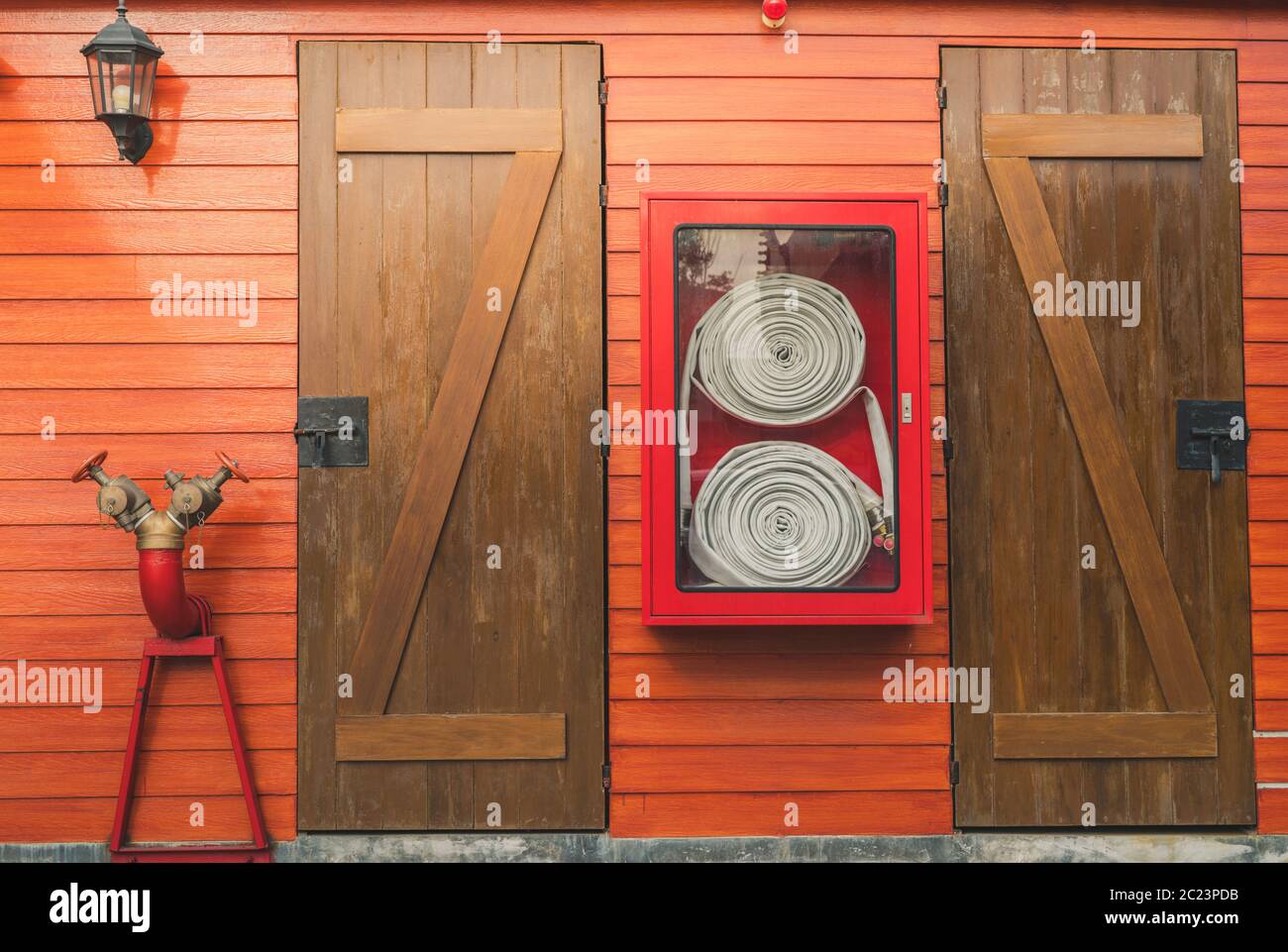 Fire hose in red cabinet hanging on orange wooden wall. Fire emergency ...