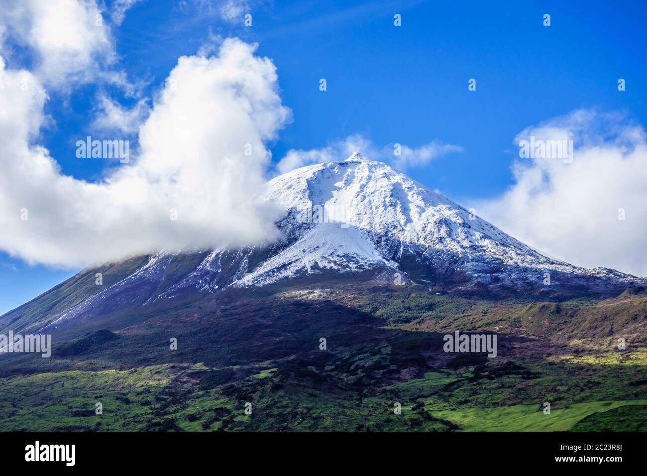Mount Pico volcano summit covered in snow under blue sky and clouds, in ...
