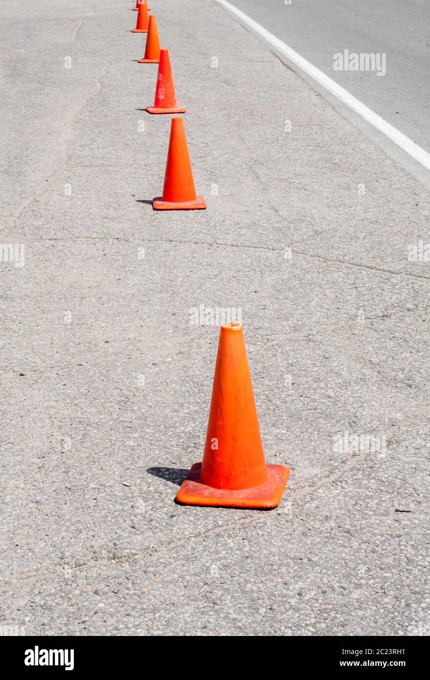 Row of orange traffic cones in perspective parallel to white line on ...