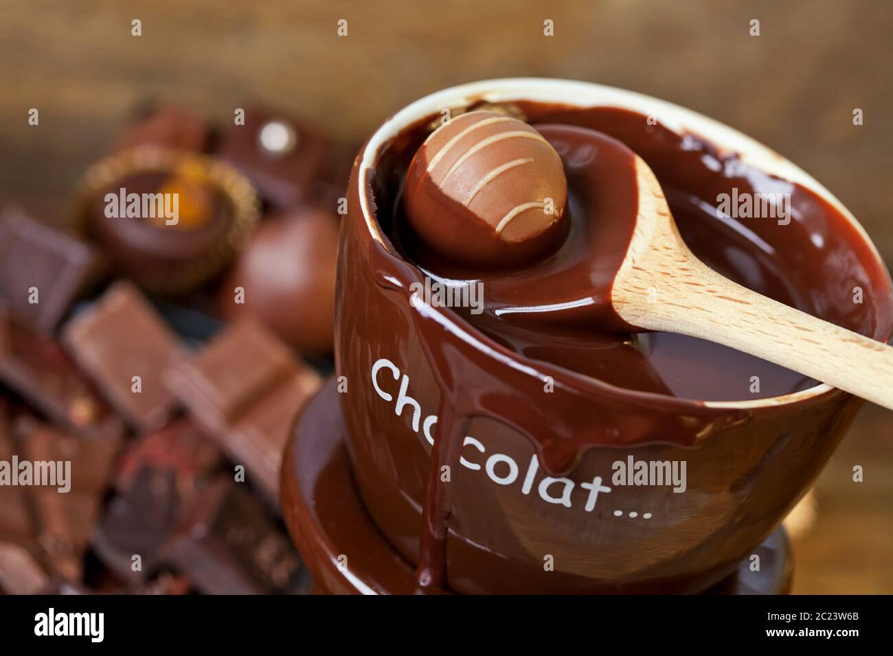 Chocolate fondue with wooden spoon and praline Stock Photo - Alamy