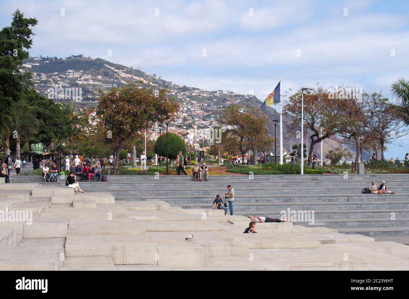 the waterfront area of funchal harbour with people sat on the concrete ...