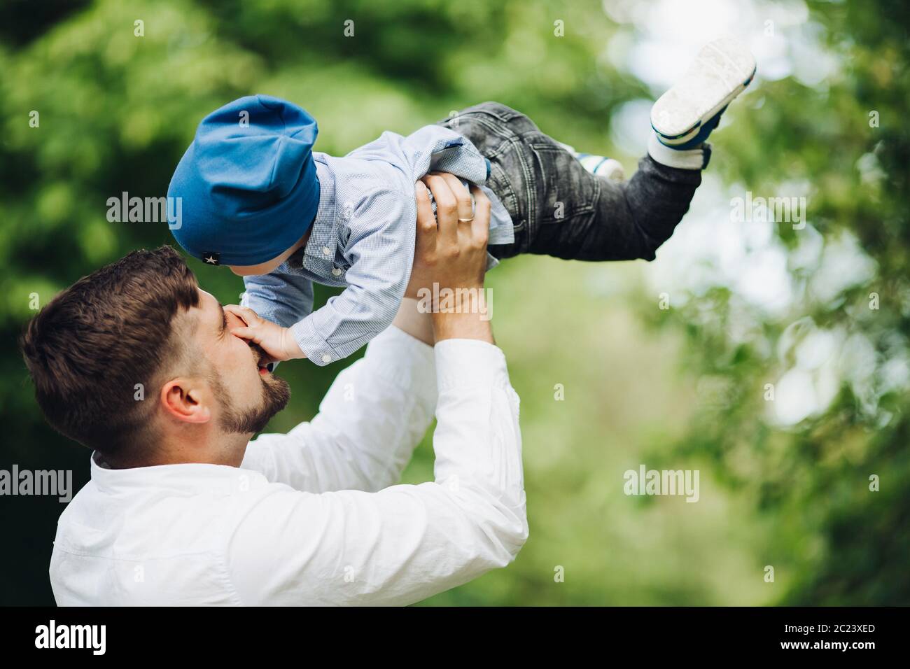 Handsome father throwing baby boy against summer park Stock Photo - Alamy