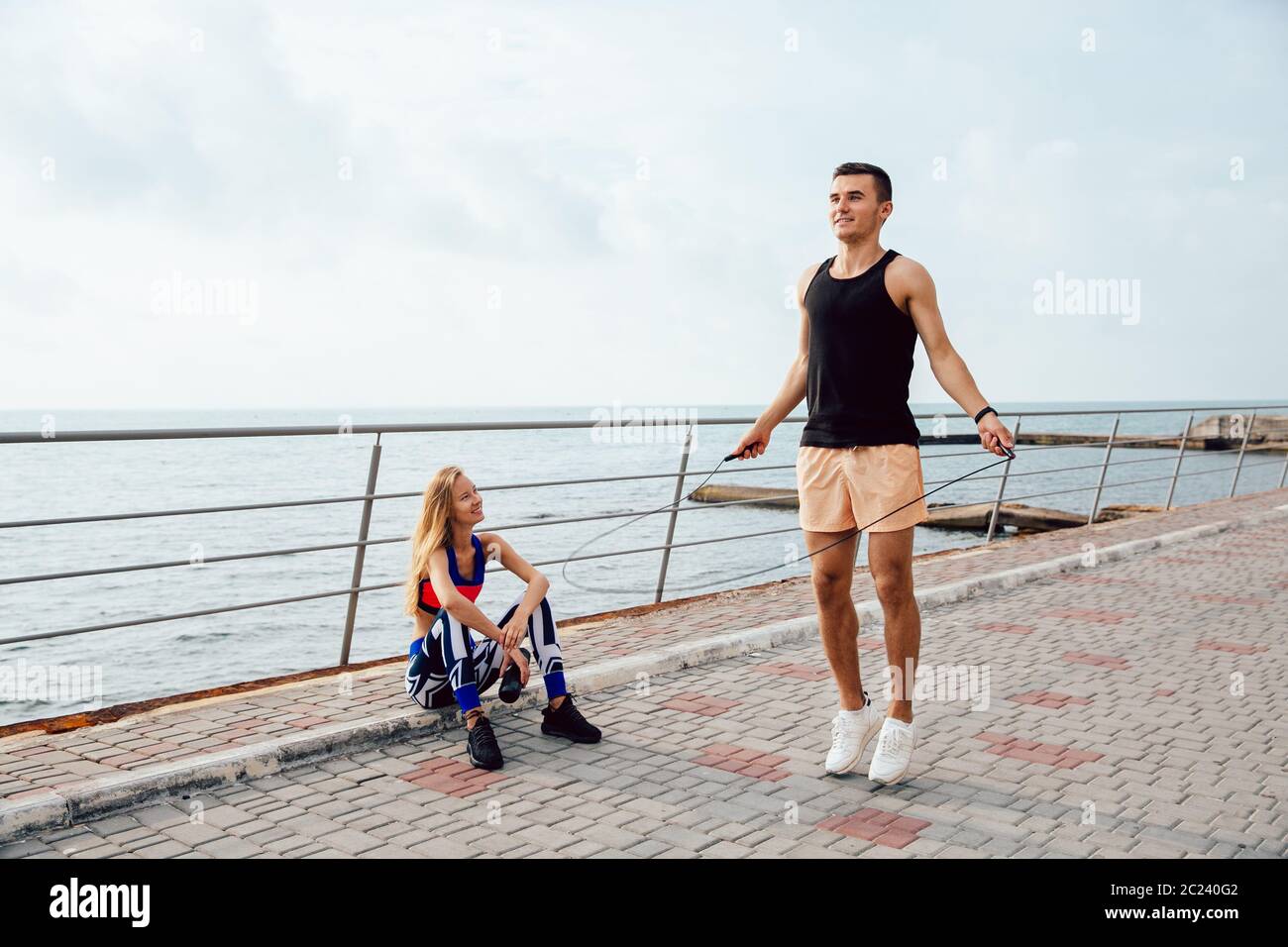 Young sportive couple working out together on the quay, near the sea ...