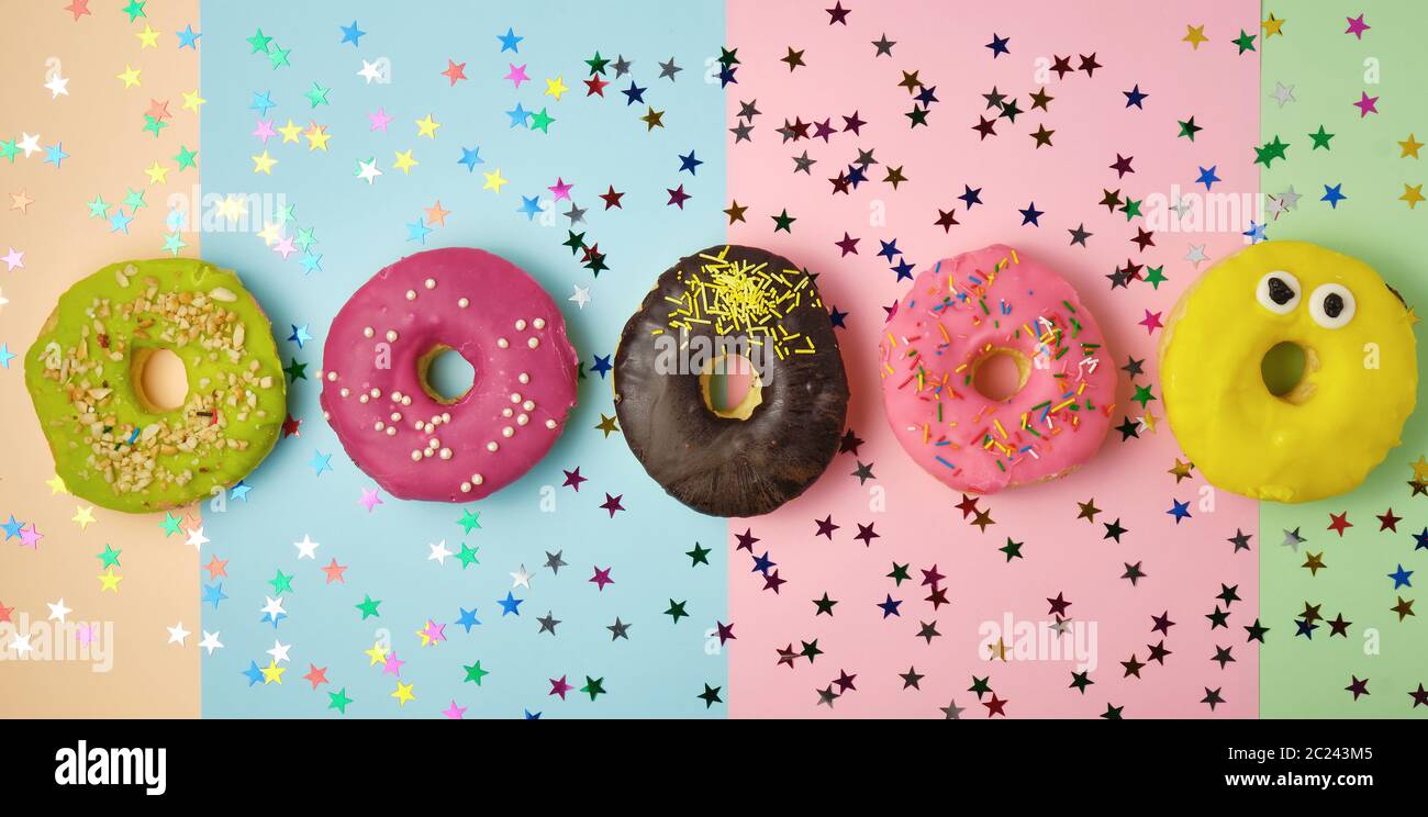 five round donuts with various fillings and sprinkles on an abstract ...