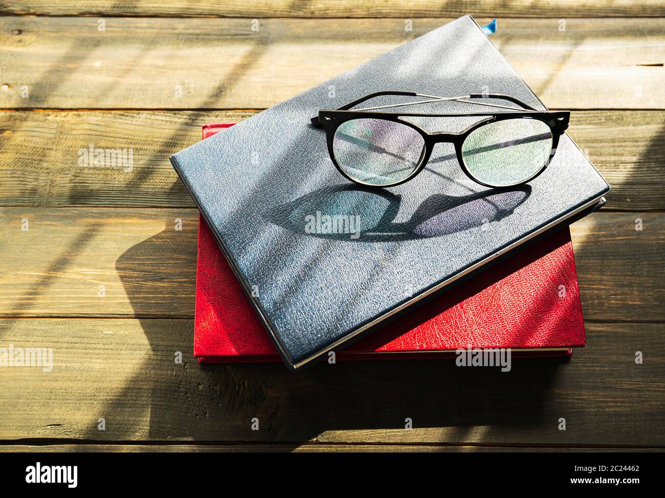 Eye glasses are placed on books on wooden table beside the window Stock ...
