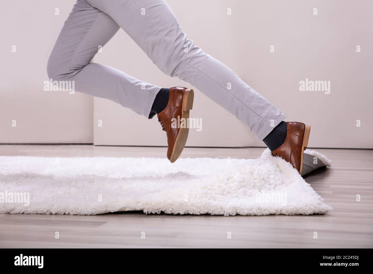 Low Section Of Man Legs Stumbling With A Carpet At Home Stock Photo - Alamy