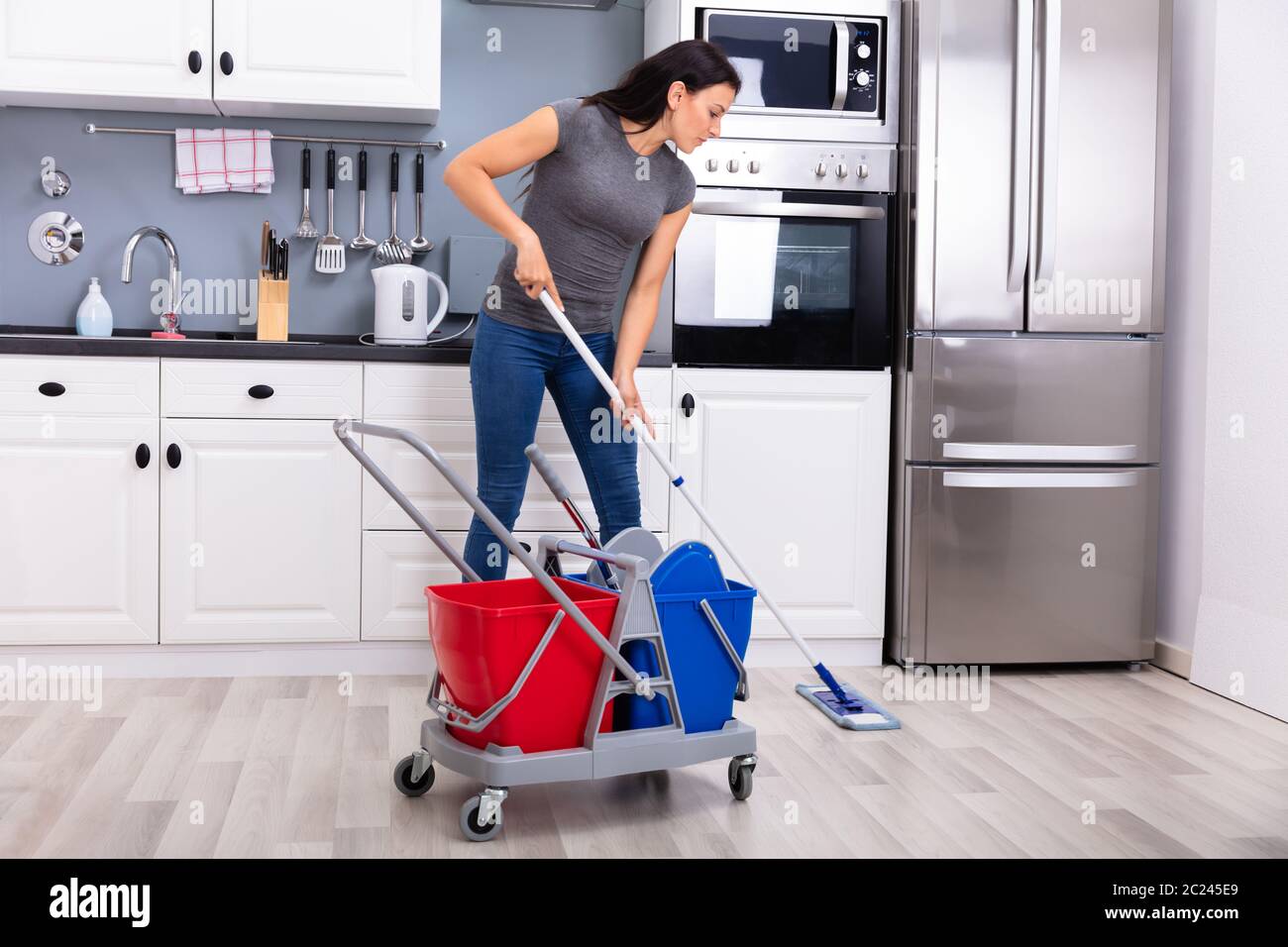Happy Female Janitor Cleaning Floor With Mop In Kitchen Stock Photo - Alamy