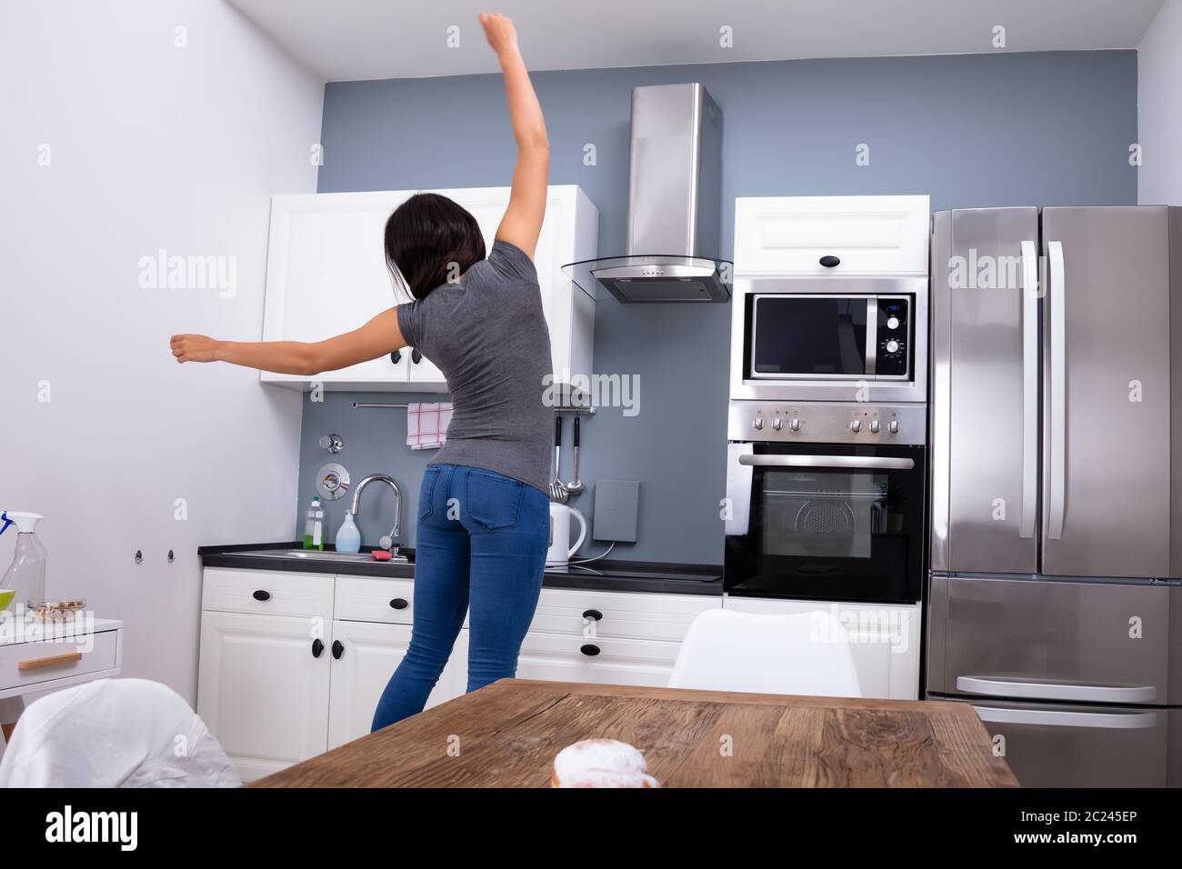 Rear View Of Young Woman Jumping In The Kitchen Stock Photo - Alamy