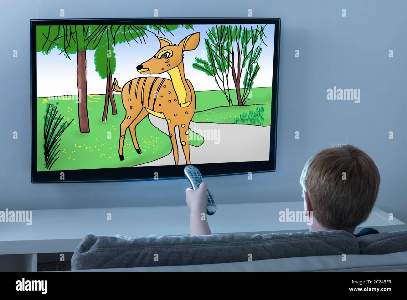 Rear View Of Boy Sitting On Sofa Watching Cartoon On Television Stock ...