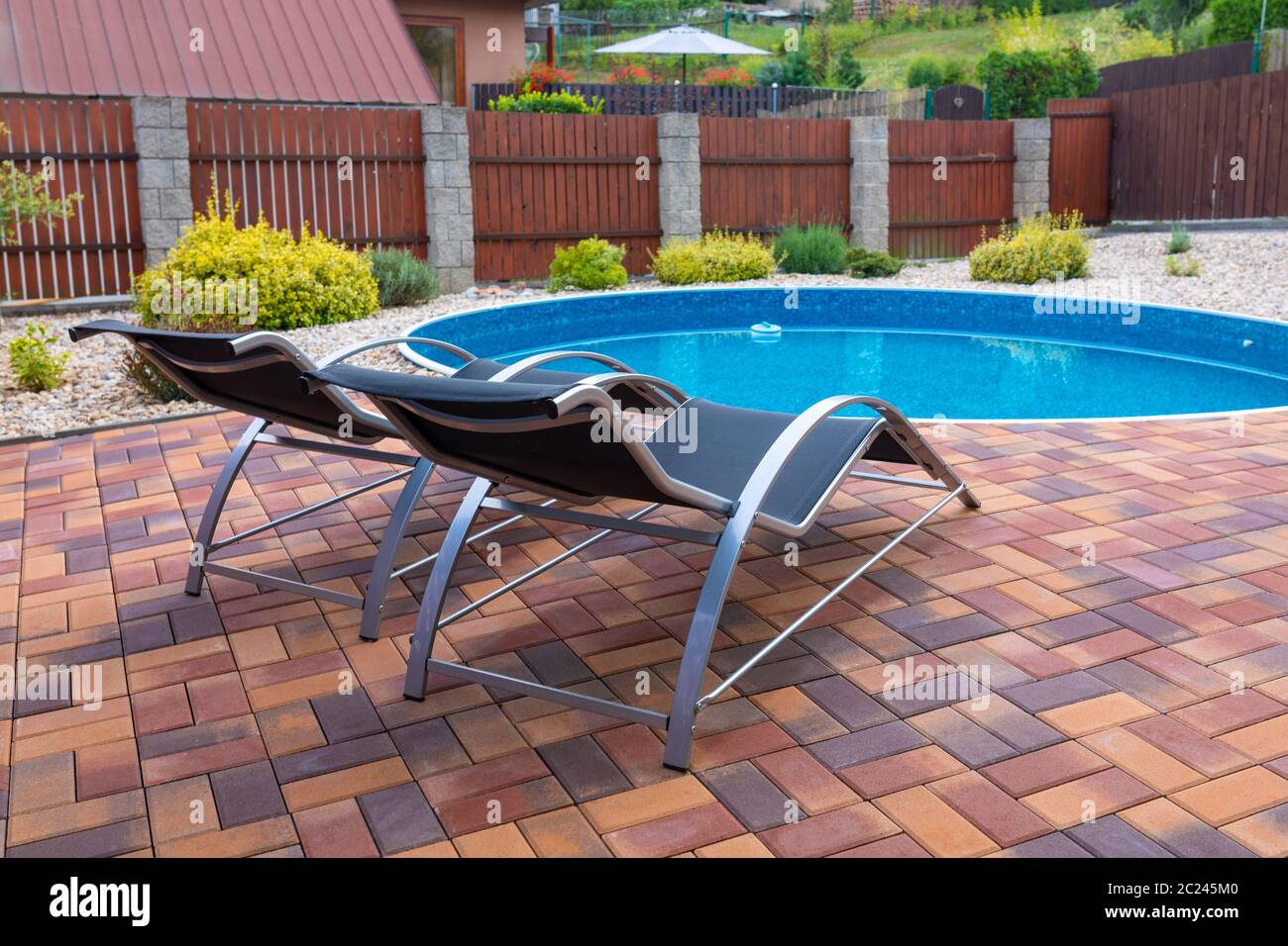 small home swimming pool with two black sun loungers Stock Photo - Alamy