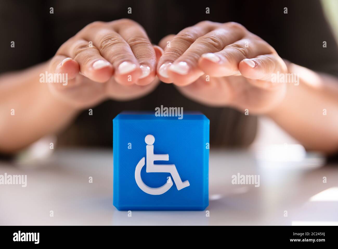 Close-up Of A Person's Hand Protecting Blue Cubic Block With Disabled ...