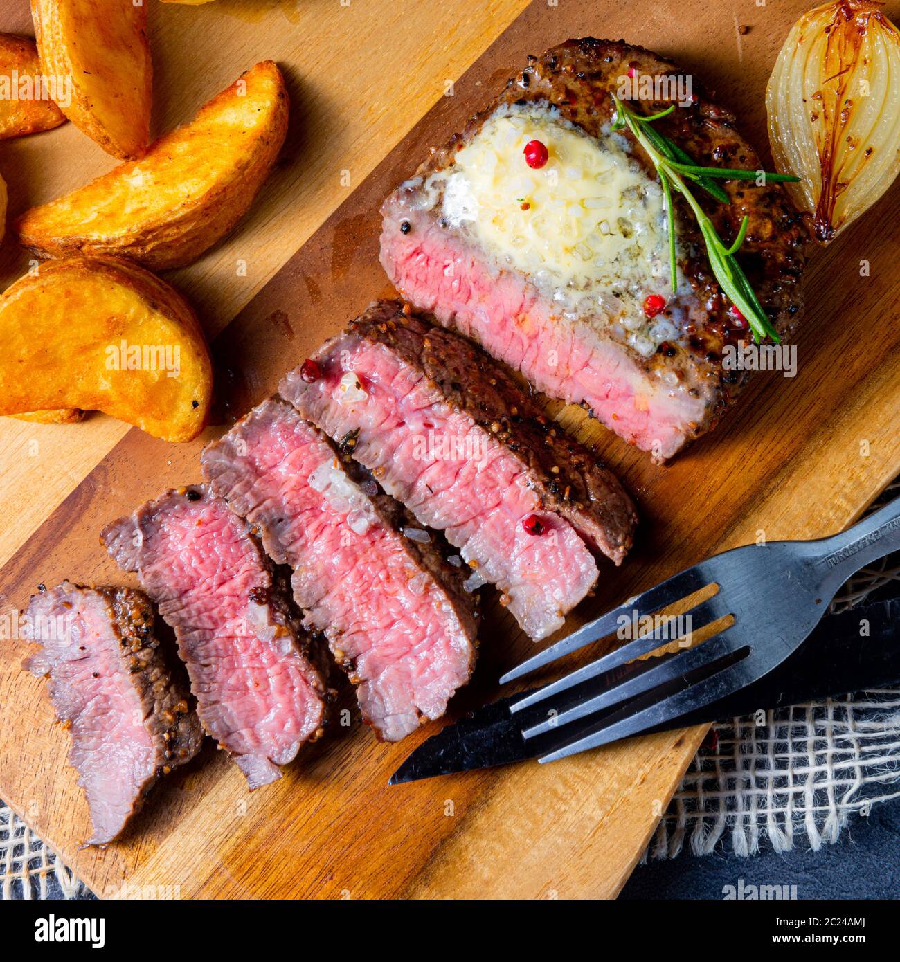 rustic medium butter beef steak with herbs and potato wedges Stock ...
