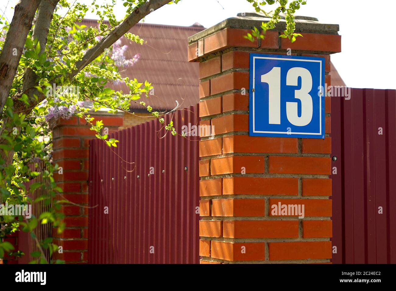 Blue color sign house number 13 on a red brick wall outdoors.Urban ...