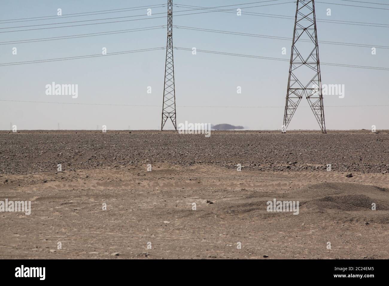 Electricity pylons in endless dry desert with shimmering air from heat ...