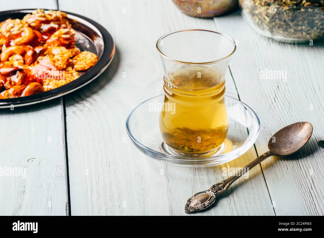 Herbal tea in armudu glass with arabic delights on metal plate over ...