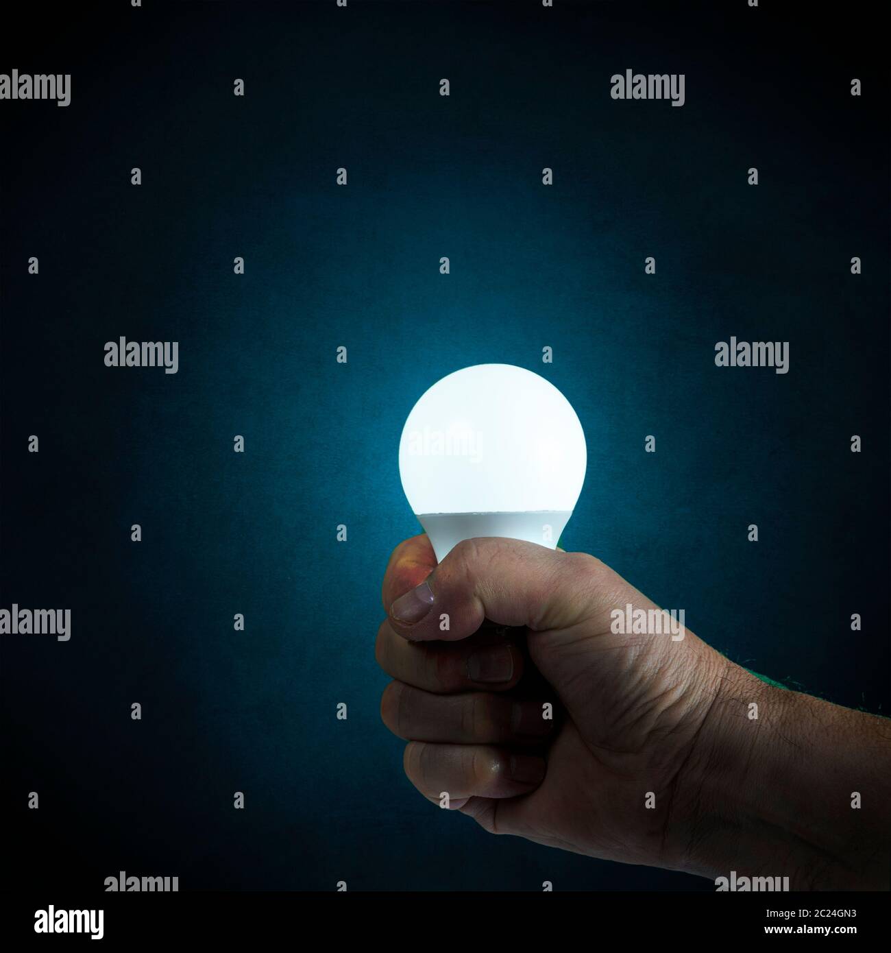 a light bulb on in hand with an antique blue background Stock Photo - Alamy