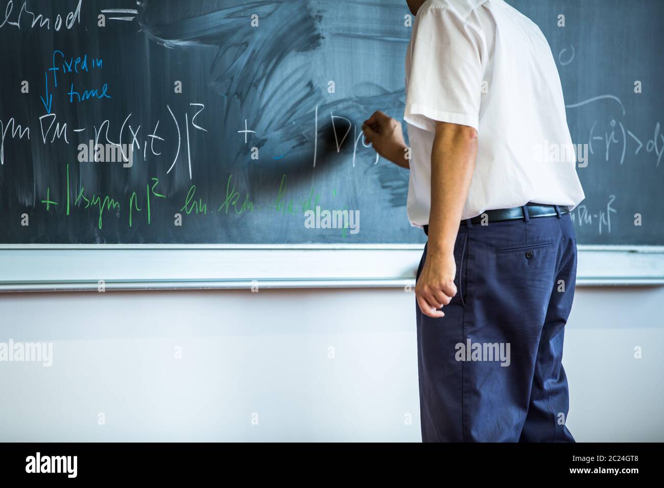 teacher teaching mathematics while pointing at blackboard in classroom ...