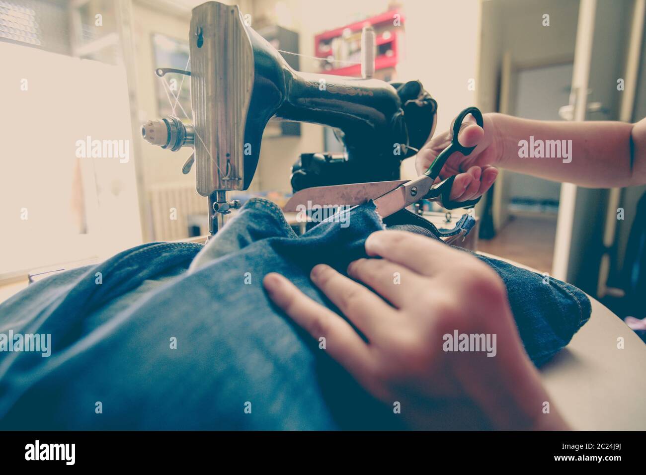 Female hands using scissors for cutting blue jeans and retro sewing ...