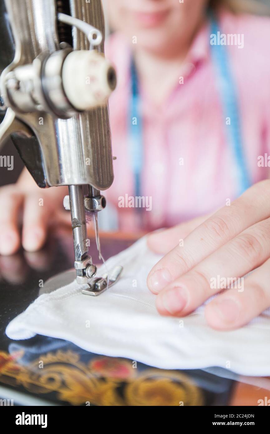 Closeup of female tailor hands working with retro sewing machine at ...