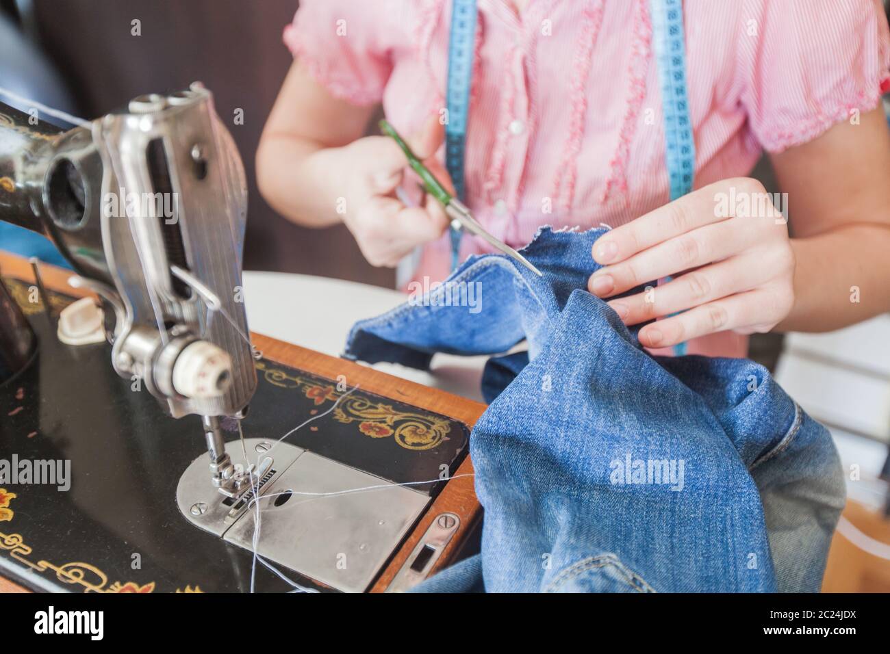 Female hands using scissors for cutting blue jeans and retro sewing ...