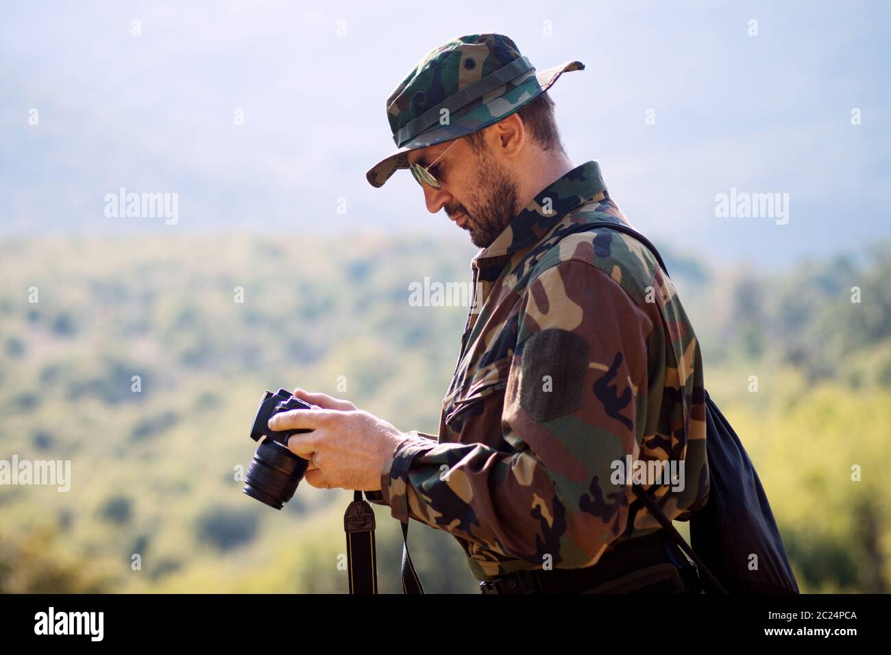 The hiker or biologist in military uniform is viewing or previewing ...