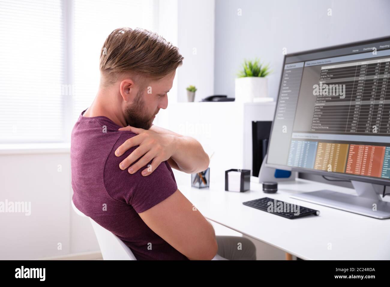 Side View Of A Young Man Sitting On Chair Suffering From Shoulder Pain ...