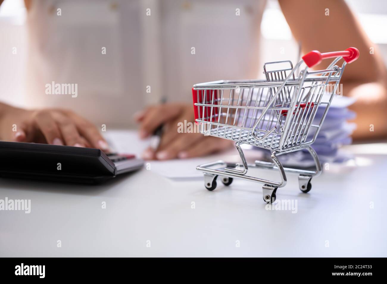 Close-up Of Person Calculating Bill With Calculator Near Shopping Cart ...