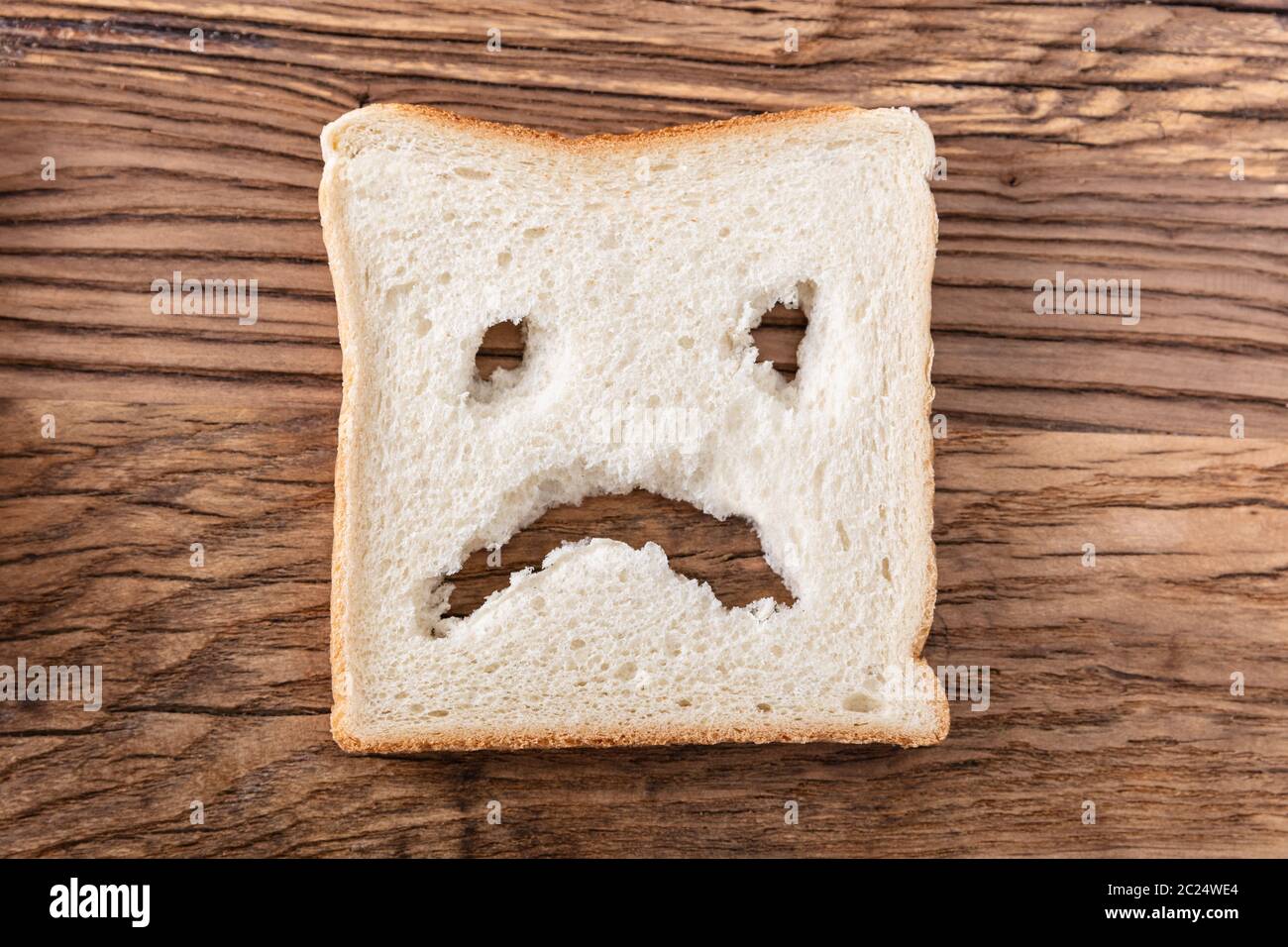 Slice Of Bread With An Unhappy Face Cut Out On Wooden Desk Stock Photo ...