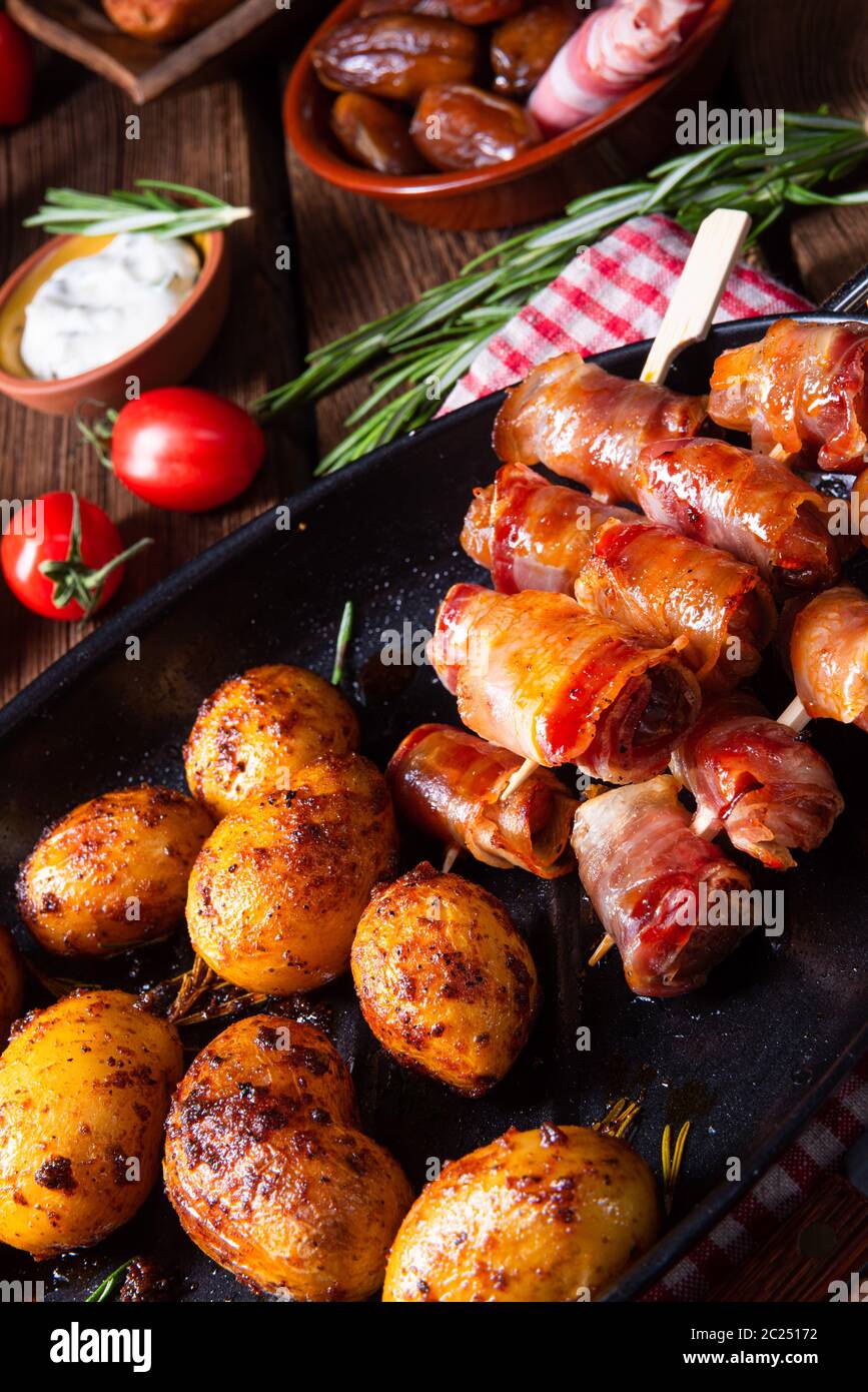 Rustic dates wrapped in bacon and young roasted potato Stock Photo - Alamy