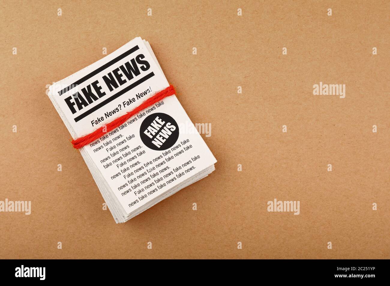 Close up stack of FAKE NEWS newspapers over brown paper background with ...