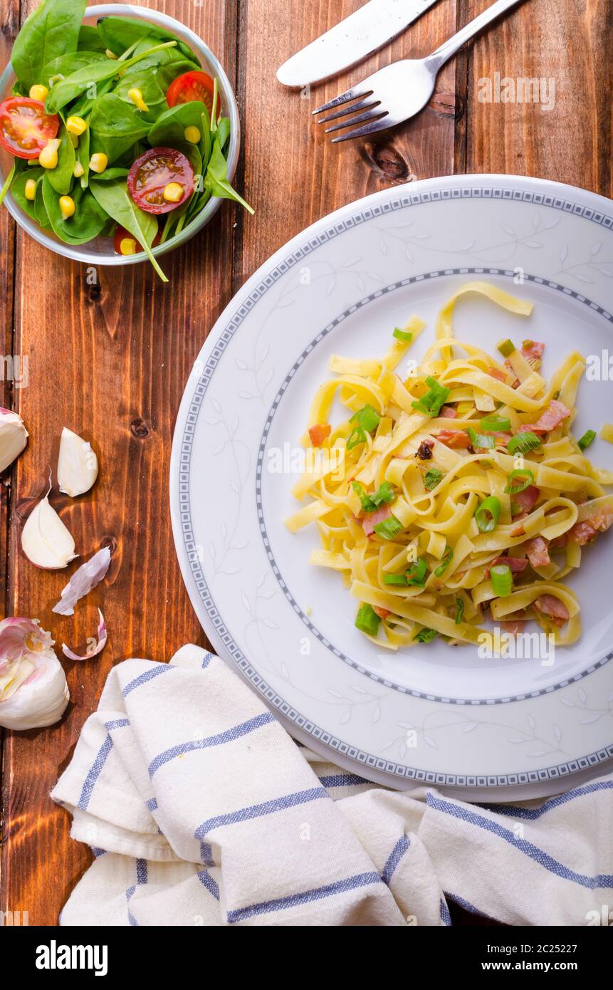 Italian pasta with spring onion, garlic and bacon with salad Stock ...