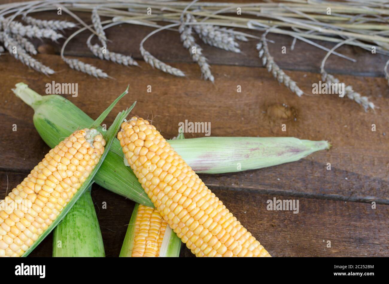 Raw corn on wood table with wheat Stock Photo - Alamy