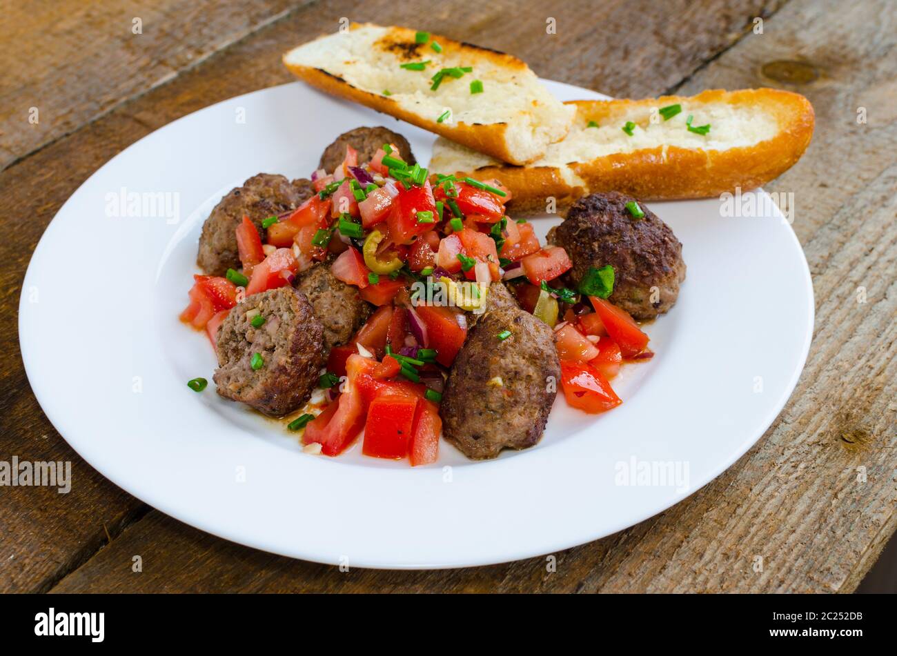 Meatballs with spicy tomato salsa, baked baguette and basil on top ...