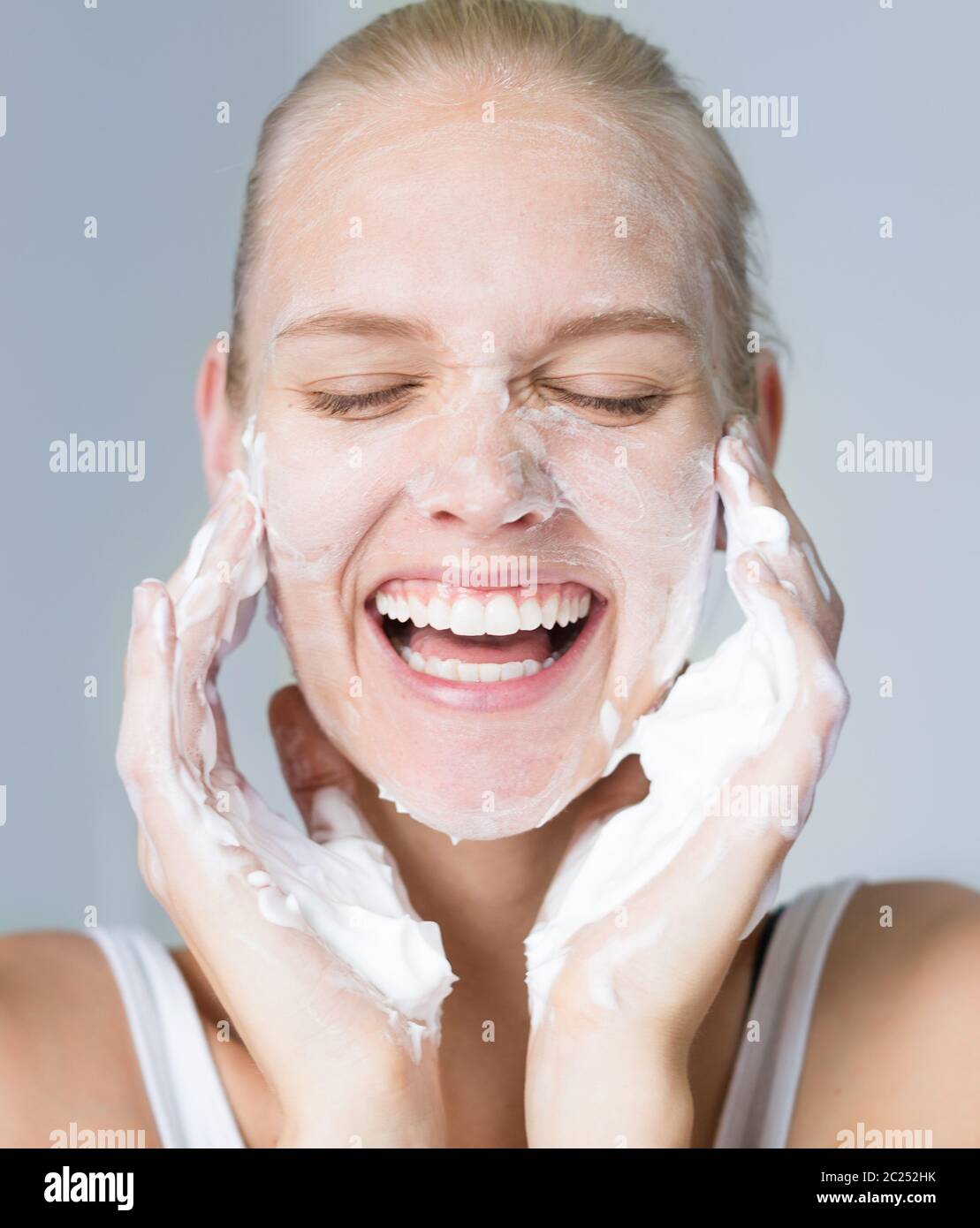 A female model splashing her face with water and soap in the bathroom ...