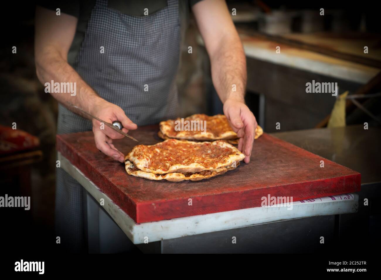Baked lahmacun is a round, thin piece of dough topped with minced meat ...