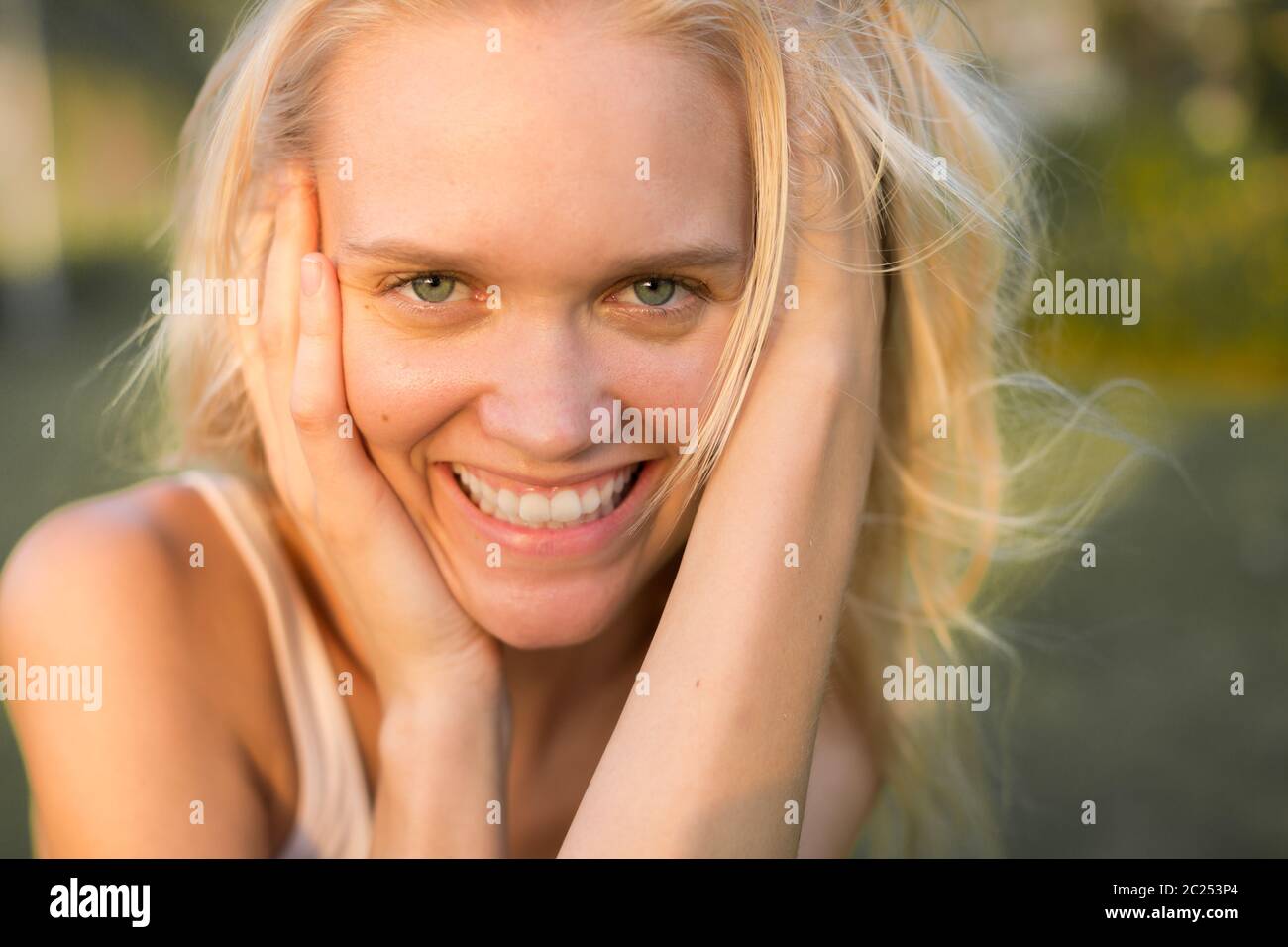 A happy young woman smiling into the camera during a warm sunny day ...