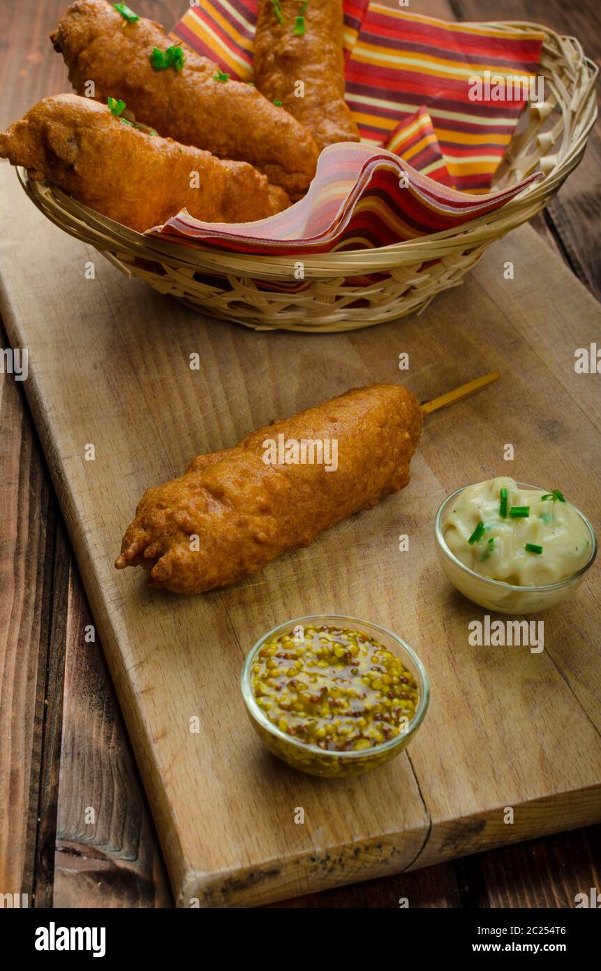 Corn dog with three sauces, chilli, mayonnaise with herbs and whole ...