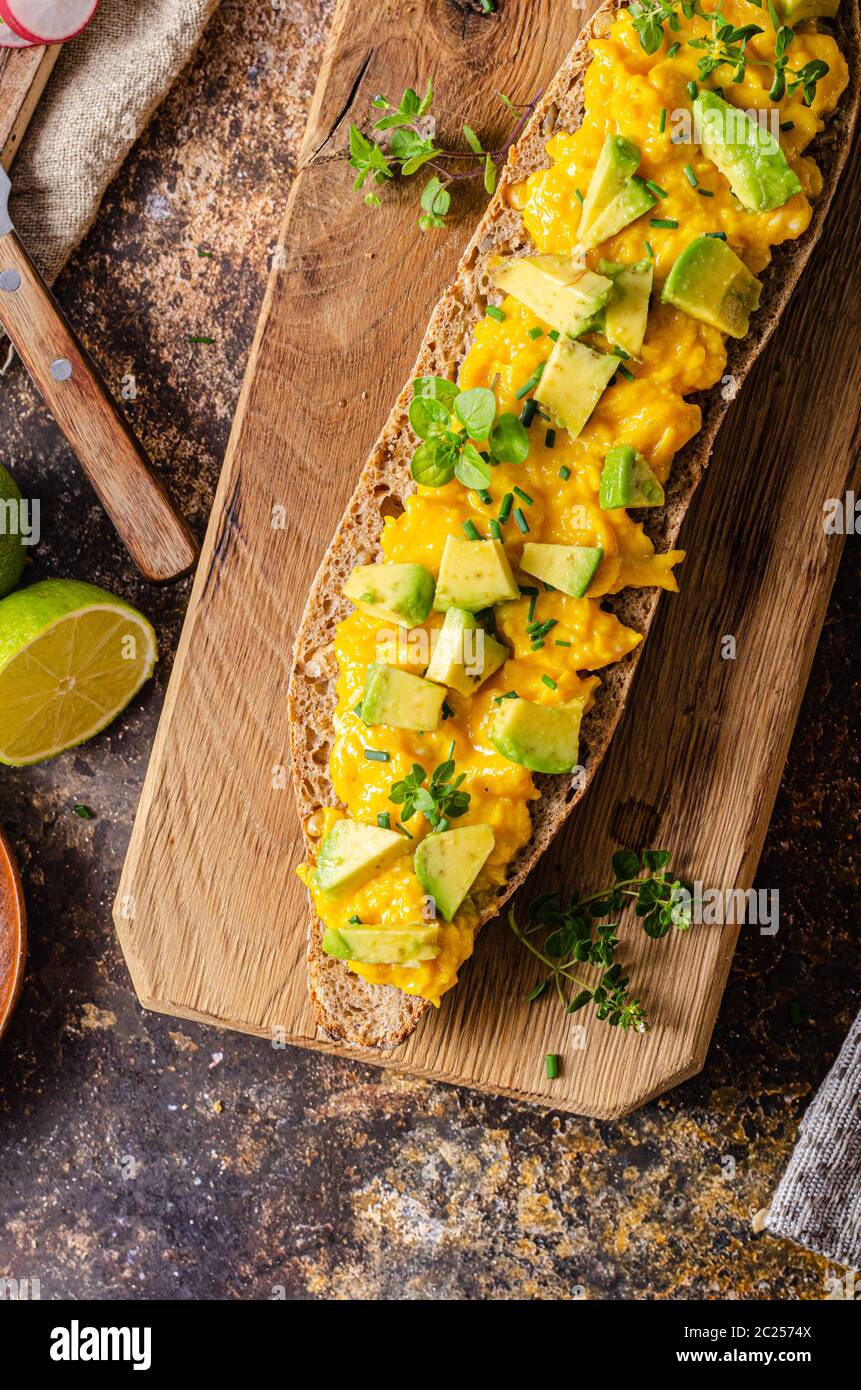 Bio scrambled eggs on rustic french baguette with fresh herbs and ...